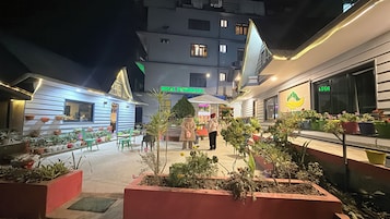 Pátio de hotel com plantas em vasos, área de estar ao ar livre e placa indicando Hotel Pathibhara.