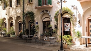 Um edifício com uma placa que diz 'LOTUS Home & Café' e área externa com mesas e cadeiras.