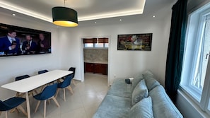 Uma sala de estar moderna com área de jantar, cozinha e uma janela ampla.