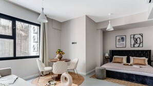 Quarto moderno com cama, mesa de cabeceira e um espaço de estar com cadeiras e mesa de centro.