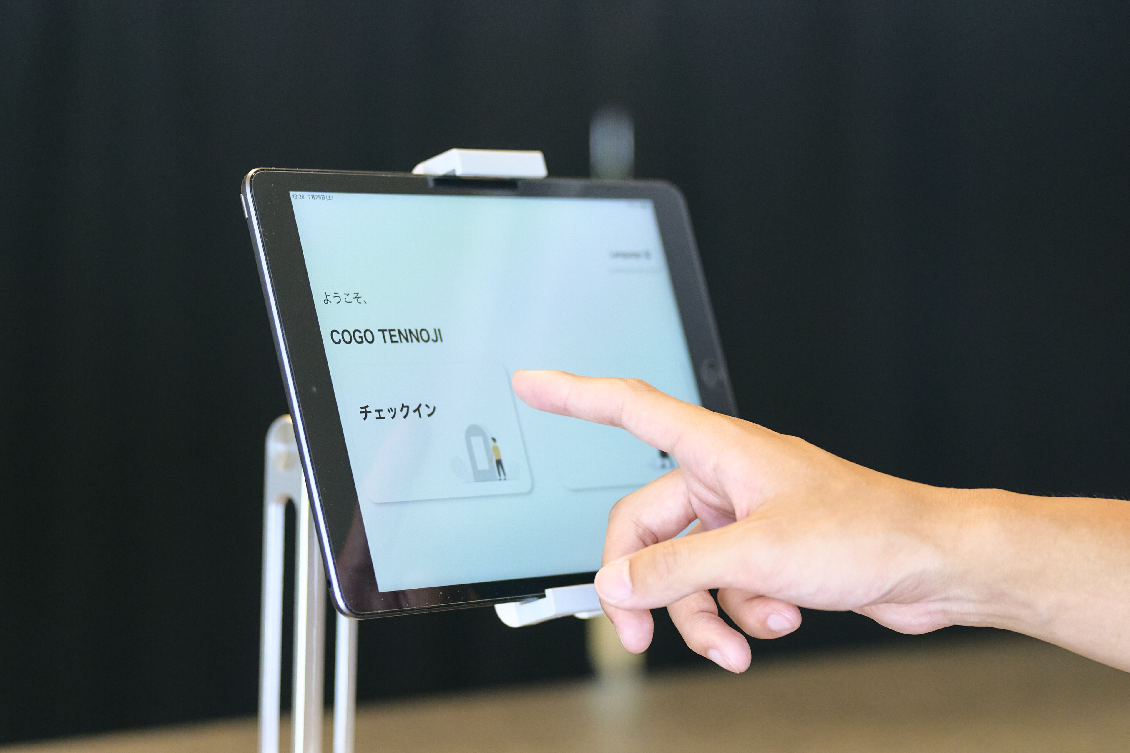 Mão segurando um tablet exibindo texto em japonês.