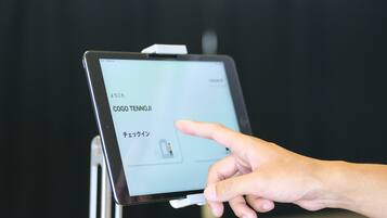Mão segurando um tablet exibindo texto em japonês.