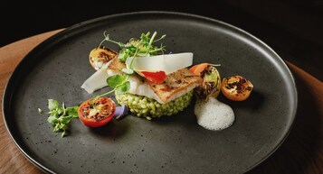 Prato de comida com legumes grelhados e uma base verde, possivelmente uma salada ou um prato com camada de base.
