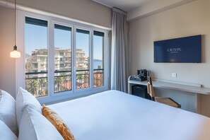 Quarto de hotel com uma cama grande, uma mesa de trabalho com máquina de café e uma TV exibindo 'CRISOL HOTELS'.
