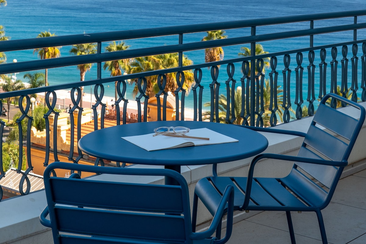 Varanda com mesa e cadeiras com vista para o mar.