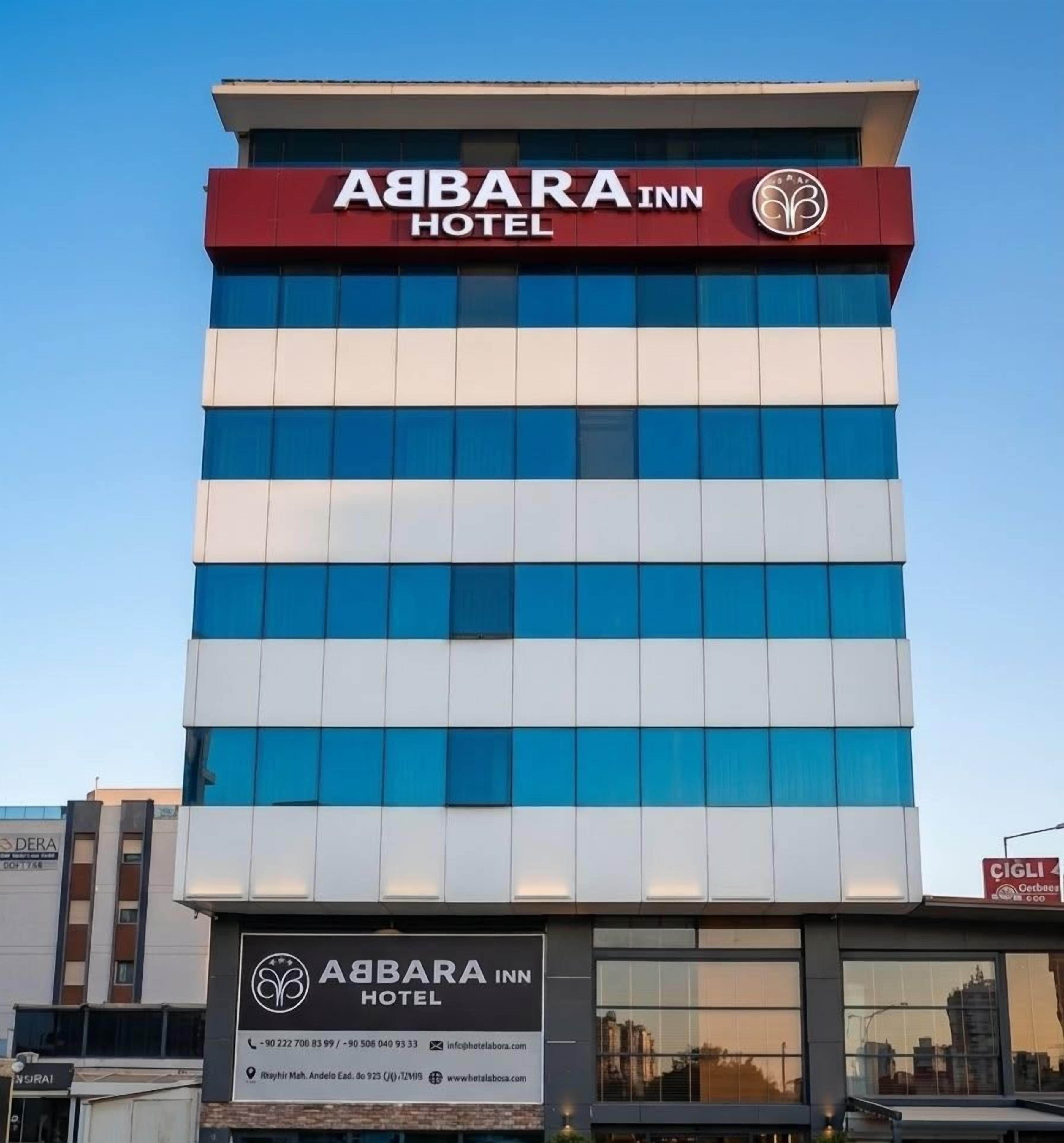 Um hotel com vários andares e uma placa chamativa com a inscrição 'ABBARA INN HOTEL'.