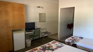 Quarto de hotel com escrivaninha, computador, cadeira e duas camas.