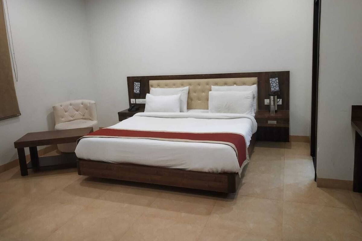 Quarto com cama grande, mesa de cabeceira, cadeira e criado-mudo.