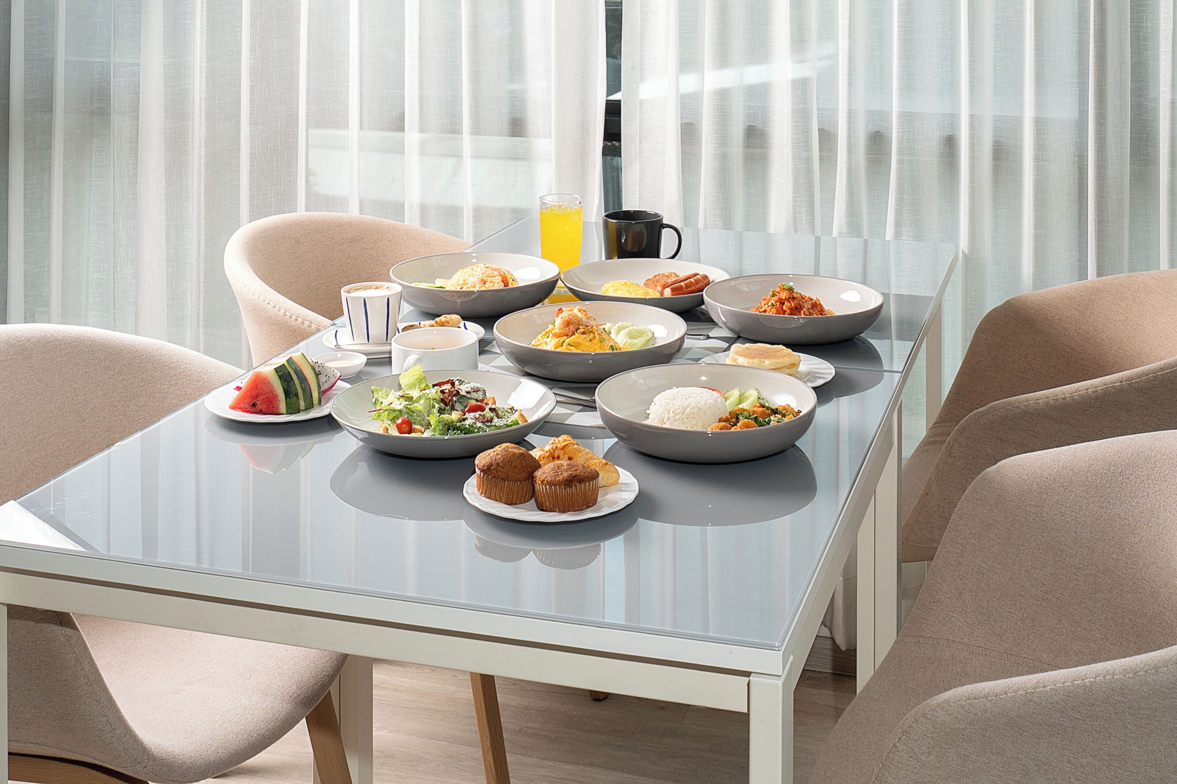 Uma mesa de jantar com diversos pratos e um copo de suco de laranja.