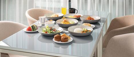 Uma mesa de jantar com diversos pratos e um copo de suco de laranja.