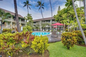 Um hotel com piscina, rodeado por vegetação exuberante e palmeiras.