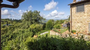 Um edifício de pedra com jardim e vista para o campo.