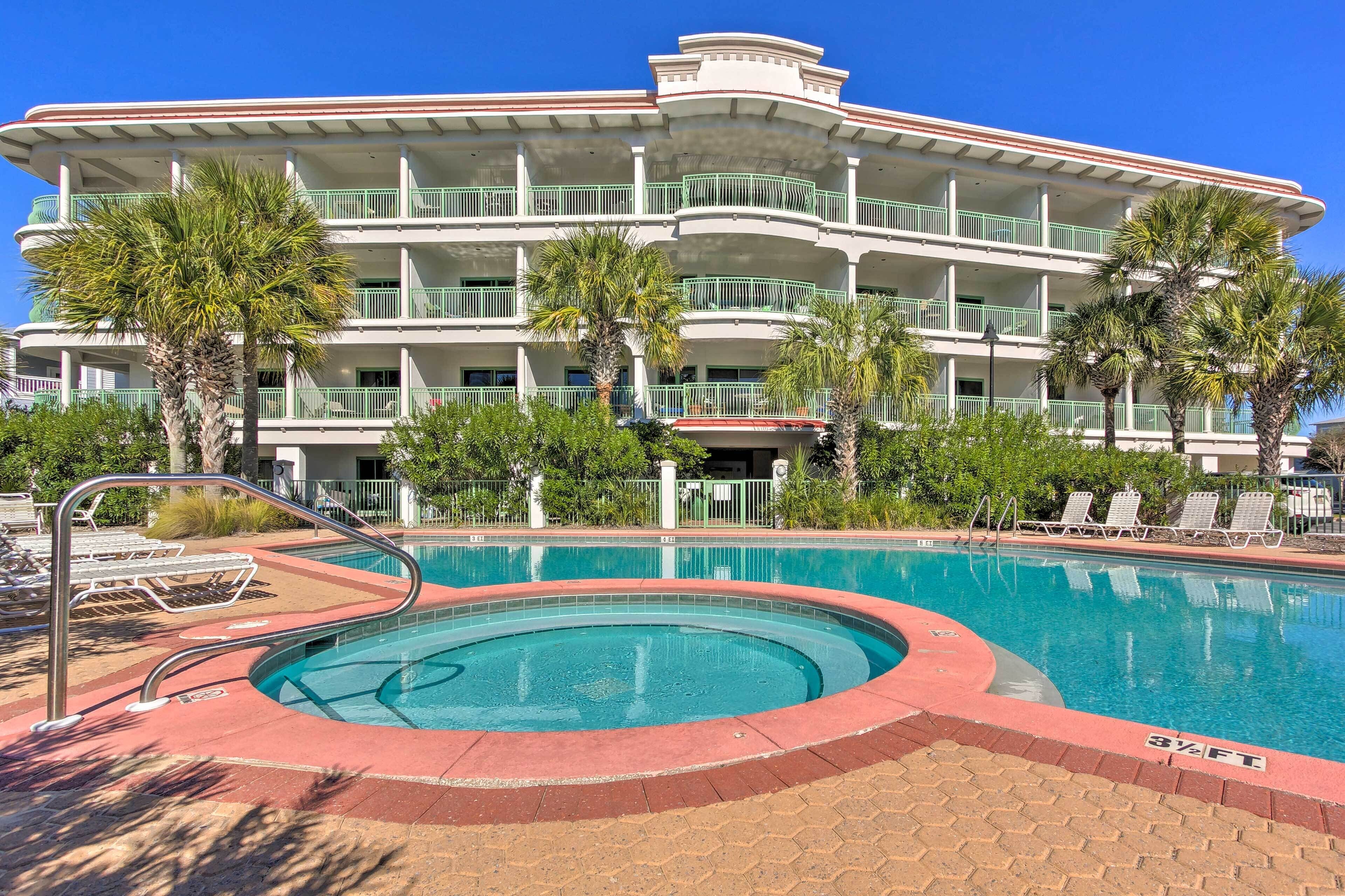 Um hotel com piscina, várias varandas e palmeiras.