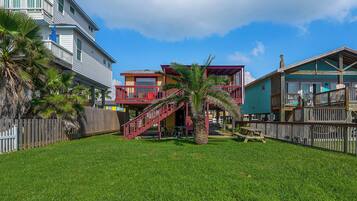 Um bairro residencial com uma casa de dois andares, destacando uma escada vermelha e um pequeno alpendre.