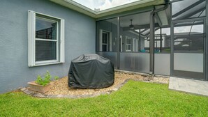 Uma casa com varanda coberta, janela com persianas e um pequeno jardim.