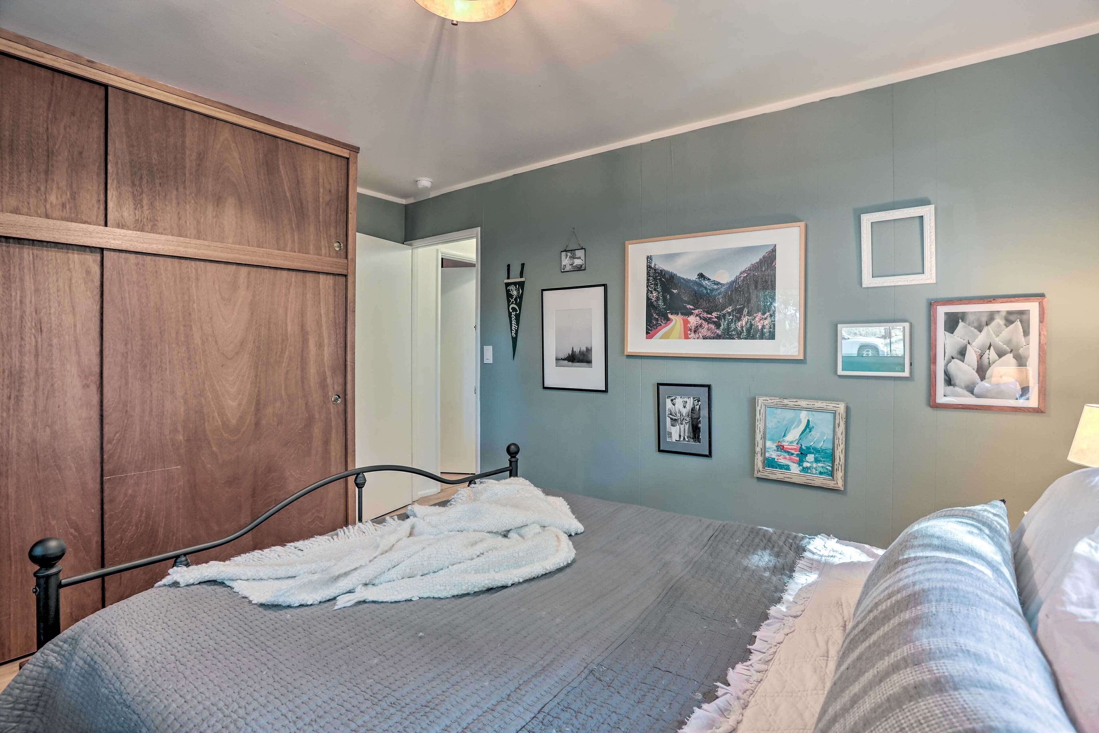 Um quarto com uma cama, um guarda-roupa e várias quadros na parede.
