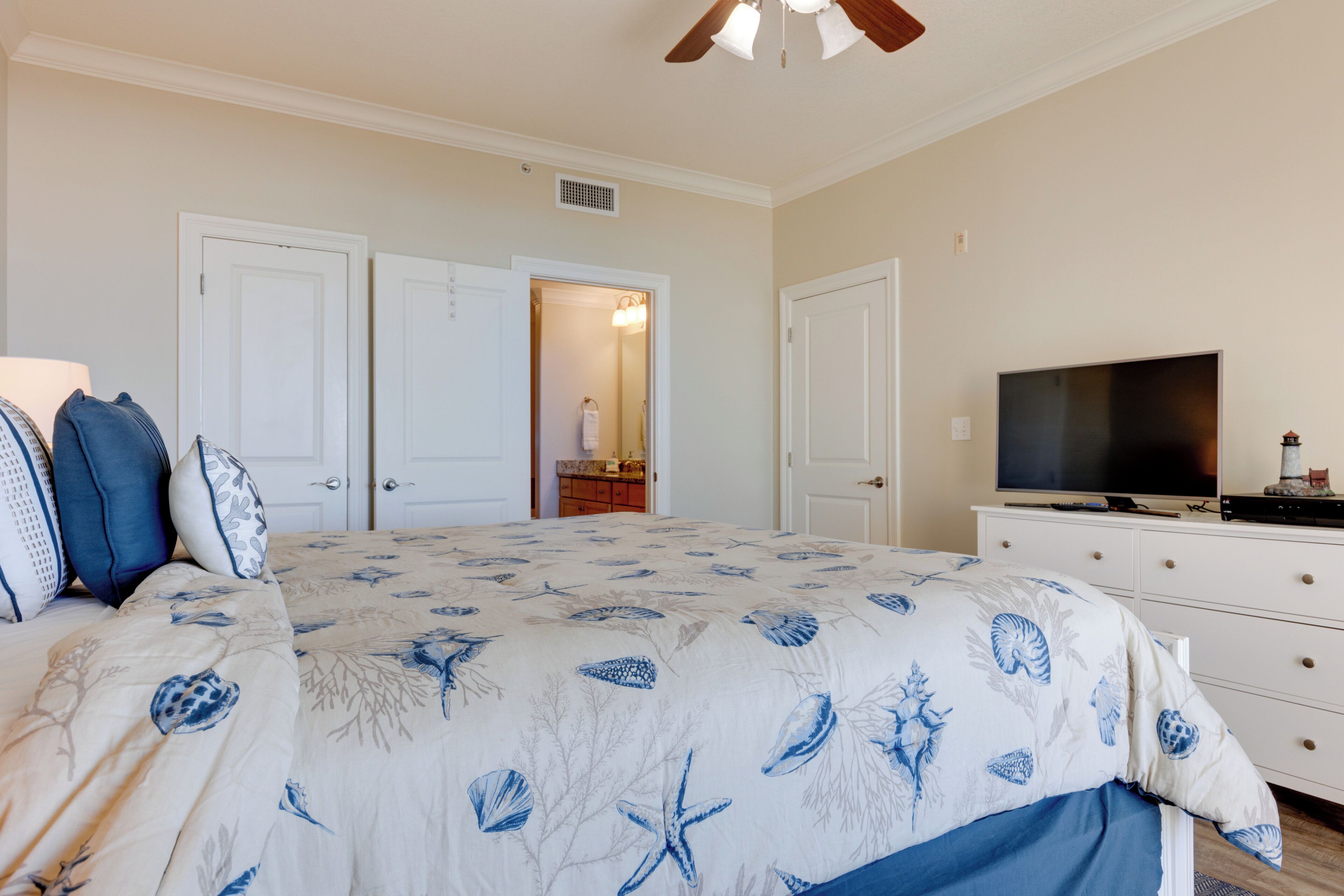 Um quarto com uma cama, uma televisão e uma cômoda.