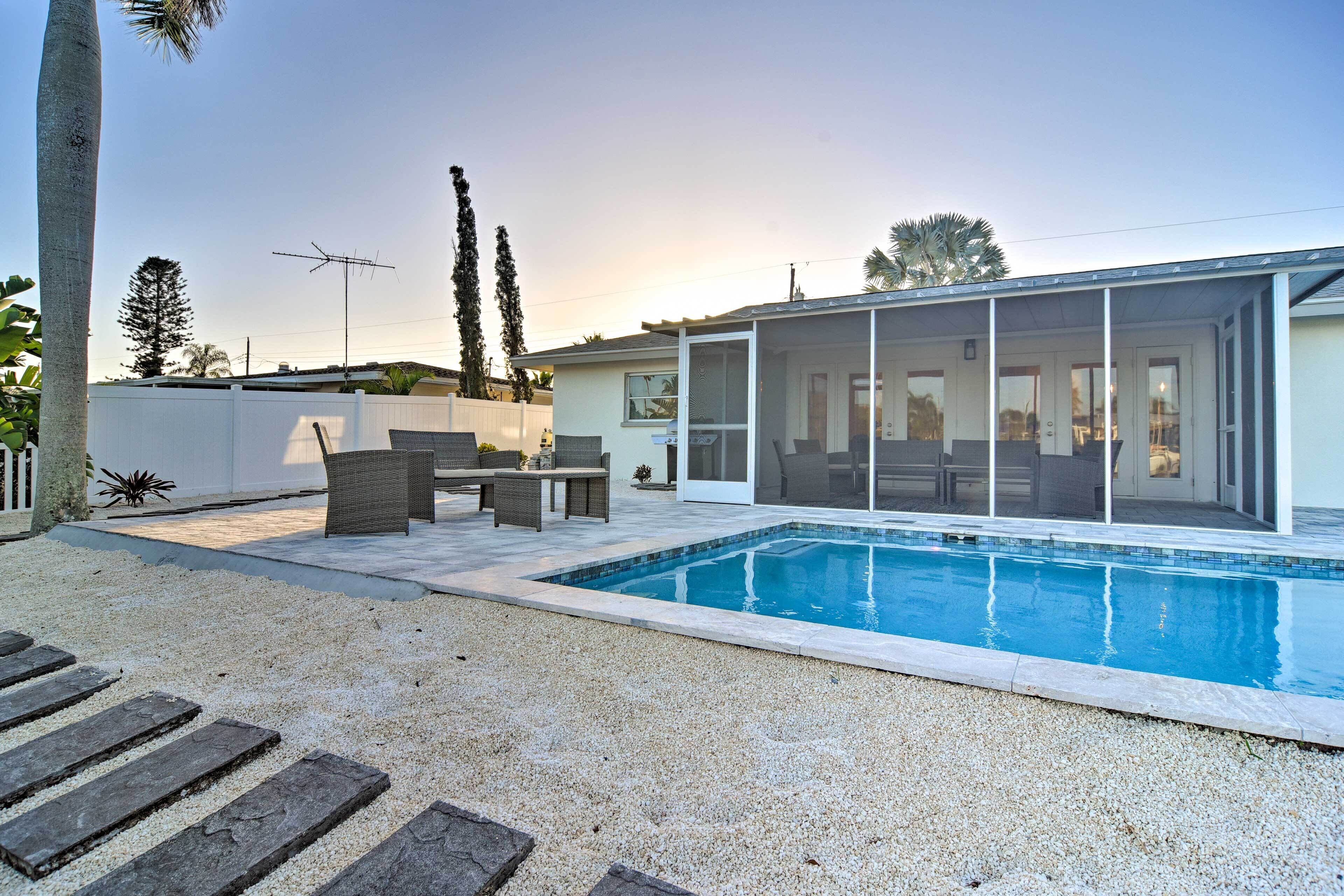 Uma casa moderna com piscina, móveis de exterior e um alpendre coberto.