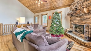 Uma sala de estar acolhedora com lareira, árvore de Natal e um sofá confortável.