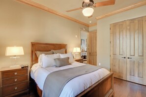 Cama bem arrumada com cabeceira de madeira, abajures e guarda-roupa de madeira.