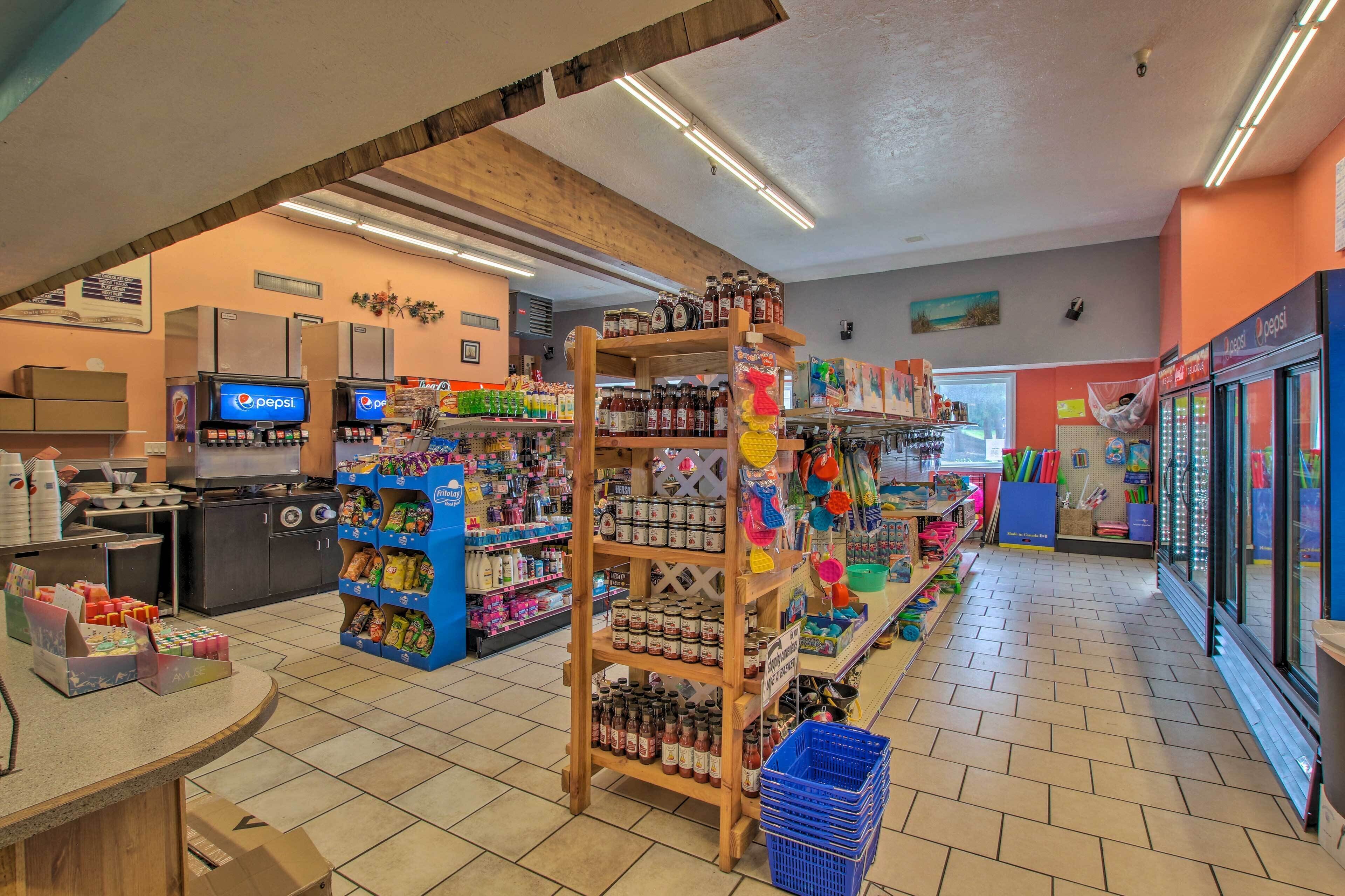 Interior de um supermercado com prateleiras repletas de diversos produtos, uma área refrigerada e um balcão de caixa.