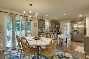 Uma cozinha moderna com área de refeições, com ilha central, cadeiras de madeira e um lustre.