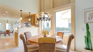 Uma sala de jantar com cadeiras de vime, uma mesa redonda e um lustre.