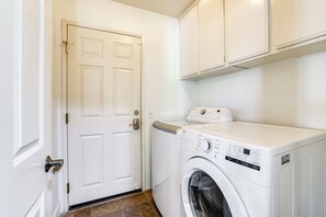 Uma lavanderia com porta branca, máquina de lavar e secadora.