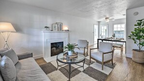 Uma sala de estar com lareira, área de jantar e vista para o exterior.