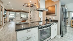 Uma cozinha moderna com ilha central, eletrodomésticos de aço inoxidável e iluminação pendente.