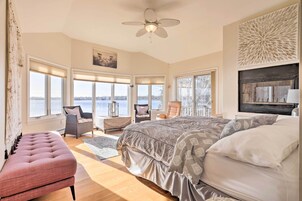 Um quarto amplo com uma cama grande, uma área de estar com cadeiras e vista para o exterior.