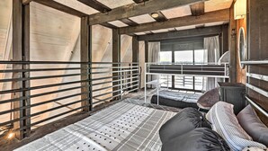 Uma cabana acolhedora com uma cama, uma pequena mesa e uma cadeira. Há uma janela com cortinas e vista para o exterior.