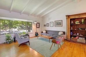 Uma sala de estar com sofá, poltronas, mesa de centro e estante de livros.