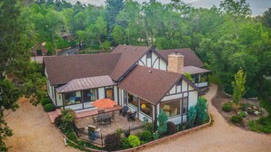 Uma casa de dois andares com alpendre coberto, chaminé de pedra e entrada com calçada de brita.