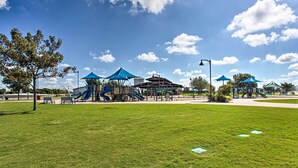 Um parque com equipamentos de playground, bancos e mesas para piquenique.