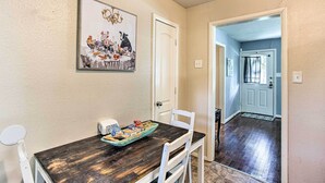 Uma sala de jantar com mesa de madeira, cadeiras brancas e um quadro na parede.