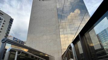 Um edifício alto com fachada de vidro e uma escadaria que leva até ele.