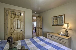 Um quarto com uma cama, cômoda, abajur, espelho e porta.