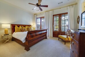 Quarto com cama de madeira, mesa de cabeceira, cômoda e cadeira.