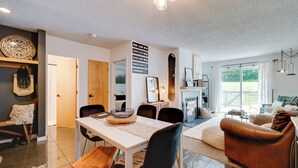 Uma sala de estar moderna com área de jantar, lareira e vista para o exterior.