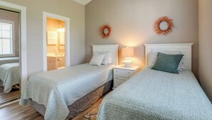 Quarto com duas camas, mesa de cabeceira com abajur e espelho.