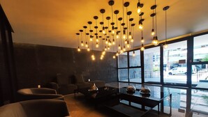 Uma sala de estar moderna com mesa de centro de vidro, sofás de couro e luminária no teto com lâmpadas aparentes.