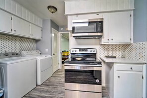 Uma cozinha compacta com forno embutido, micro-ondas e máquina de lavar roupa.