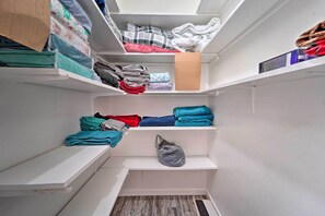 Um armário com prateleiras e gavetas contendo roupas dobradas e uma caixa de papelão.