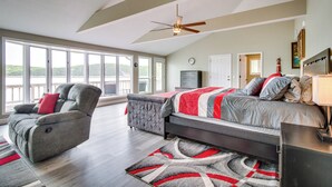 Quarto espaçoso com uma cama grande, uma poltrona reclinável e vista para o exterior através de amplas janelas.