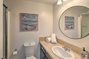Casa de banho com sanita, lavatório e duas pinturas nas paredes.