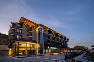 Um hotel moderno com fachada de vidro, várias varandas e um letreiro chamativo 'ARCHAZOR'.