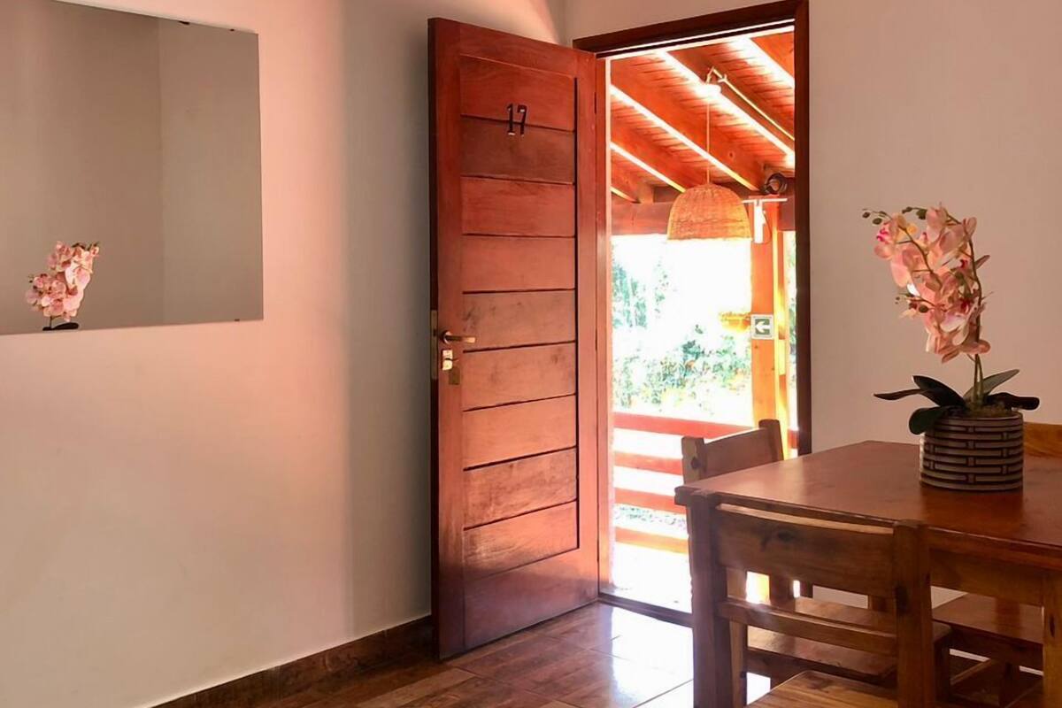 Uma mesa de jantar de madeira com cadeiras, uma porta de madeira com um número e um lustre pendurado.