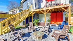 Uma área de pátio com móveis de exterior, um deck de madeira e um guarda-sol vermelho.