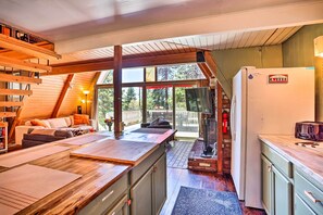 Uma cozinha acolhedora com bancada de madeira, geladeira e um espaço de refeições com mesa e cadeiras.